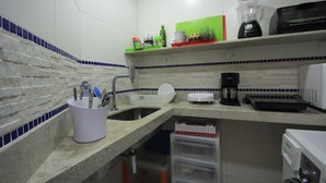Uma cozinha com bancada de granito, pia, cafeteira e micro-ondas.