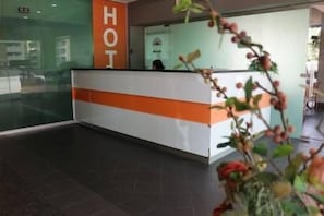 Um balcão de recepção com uma placa que diz "HOTEL" e uma divisória de vidro.