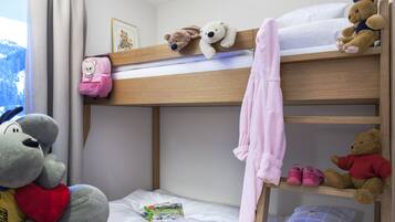 Quarto com beliche, um urso de pelúcia no colchão superior, uma toalha rosa e um cão de pelúcia no colchão inferior.