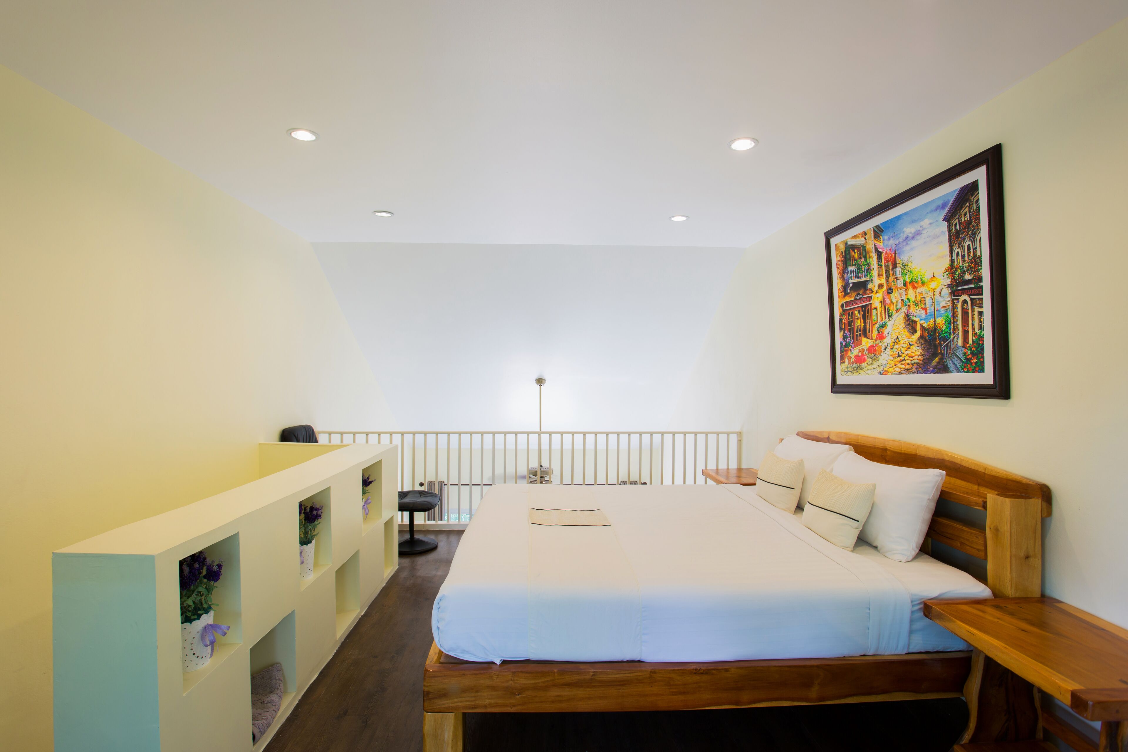 Quarto com uma cama grande, cabeceira de madeira, pintura na parede e estantes embutidas decoradas com flores.