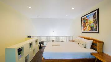 Quarto com uma cama grande, cabeceira de madeira, pintura na parede e estantes embutidas decoradas com flores.