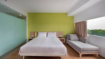 Quarto moderno com uma cama grande, um sofá e uma mesinha de cabeceira.