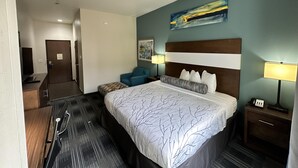 Quarto de hotel com uma cama grande, uma escrivaninha, uma cadeira e uma televisão.