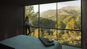 Quarto com uma grande janela que oferece vista para uma paisagem montanhosa.