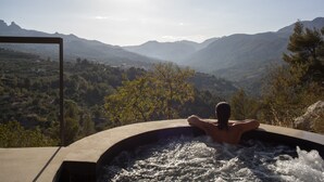 Uma pessoa relaxando em uma banheira de hidromassagem com vista panorâmica das montanhas.