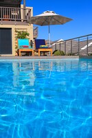 Piscina límpida com espreguiçadeiras e guarda-sóis.
