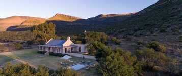 Uma casa com piscina, cercada por árvores e colinas.