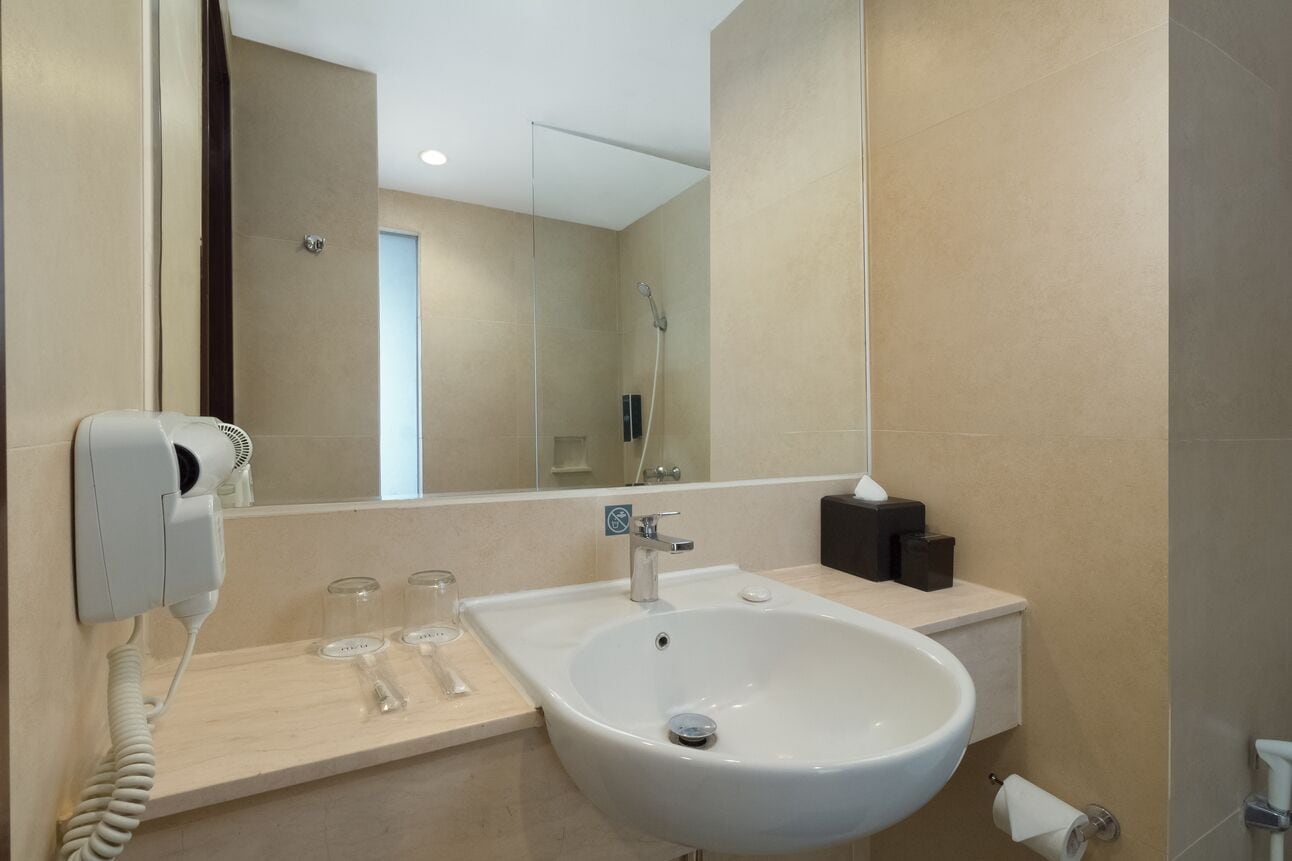Uma casa de banho moderna com uma grande pia, secador de cabelo e espelho.