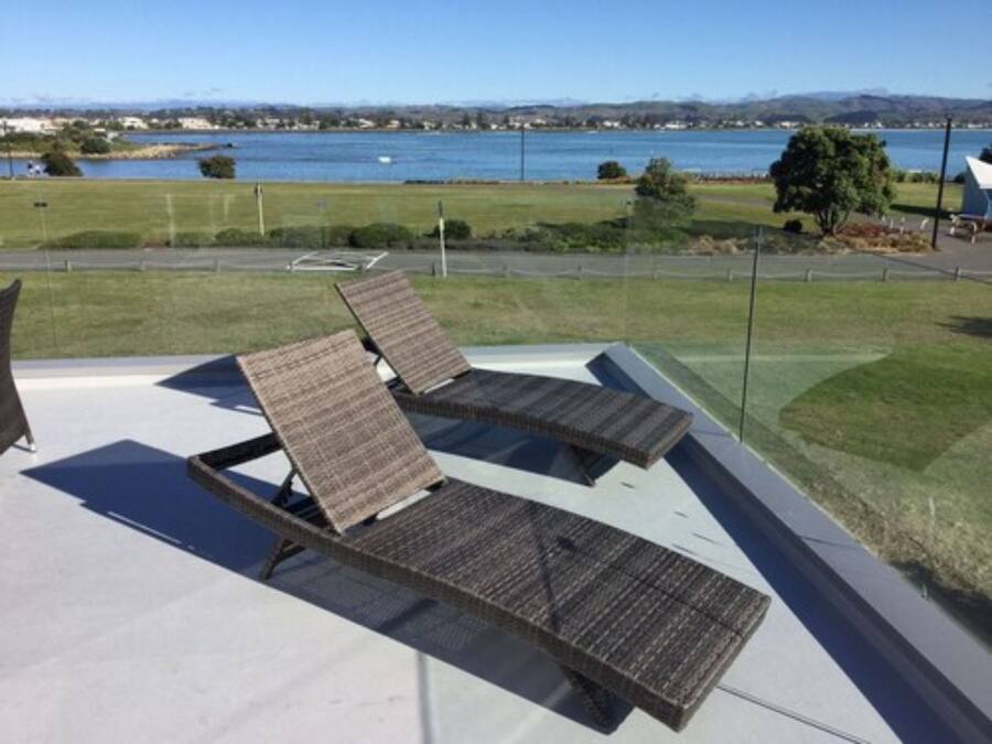 Terraço no telhado com três cadeiras de descanso e vista para um lago e colinas ao longe.