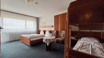 Quarto de hotel com cama, escrivaninha com cadeira e guarda-roupa.