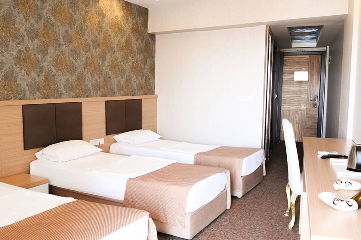 Quarto de hotel com duas camas de solteiro, uma escrivaninha e uma cadeira.