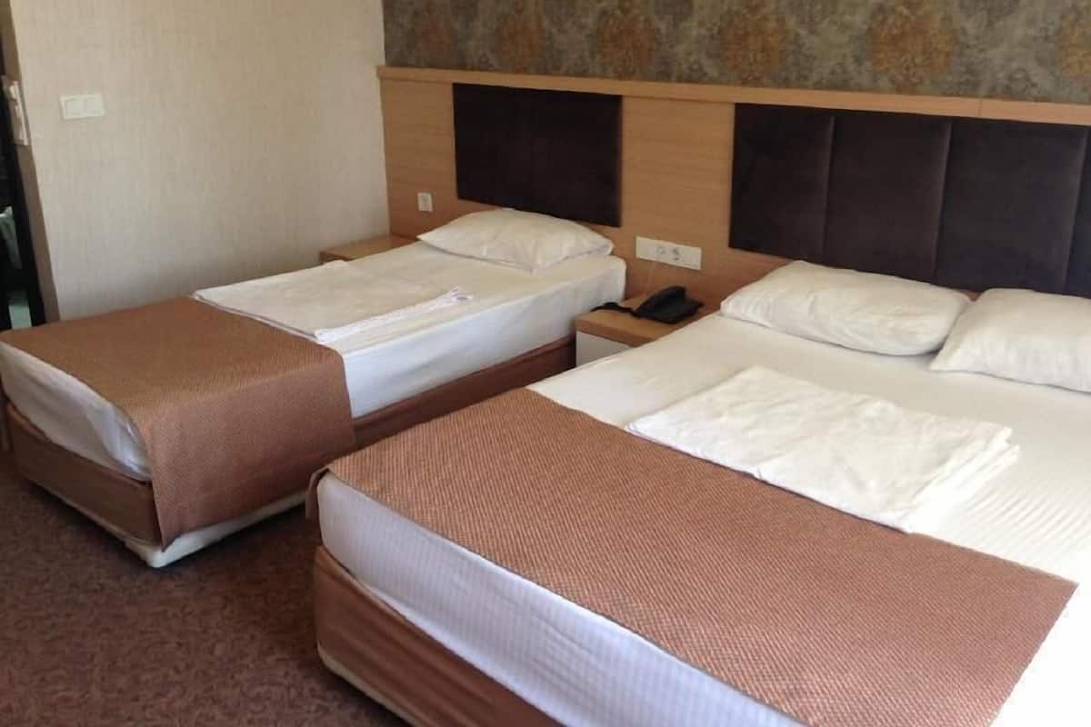 Duas camas de casal com cabeceiras marrons e roupa de cama branca em um quarto de hotel.