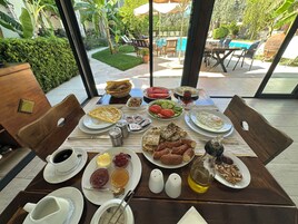 Uma mesa de jantar com diversos pratos, uma xícara de café e acompanhamentos.
