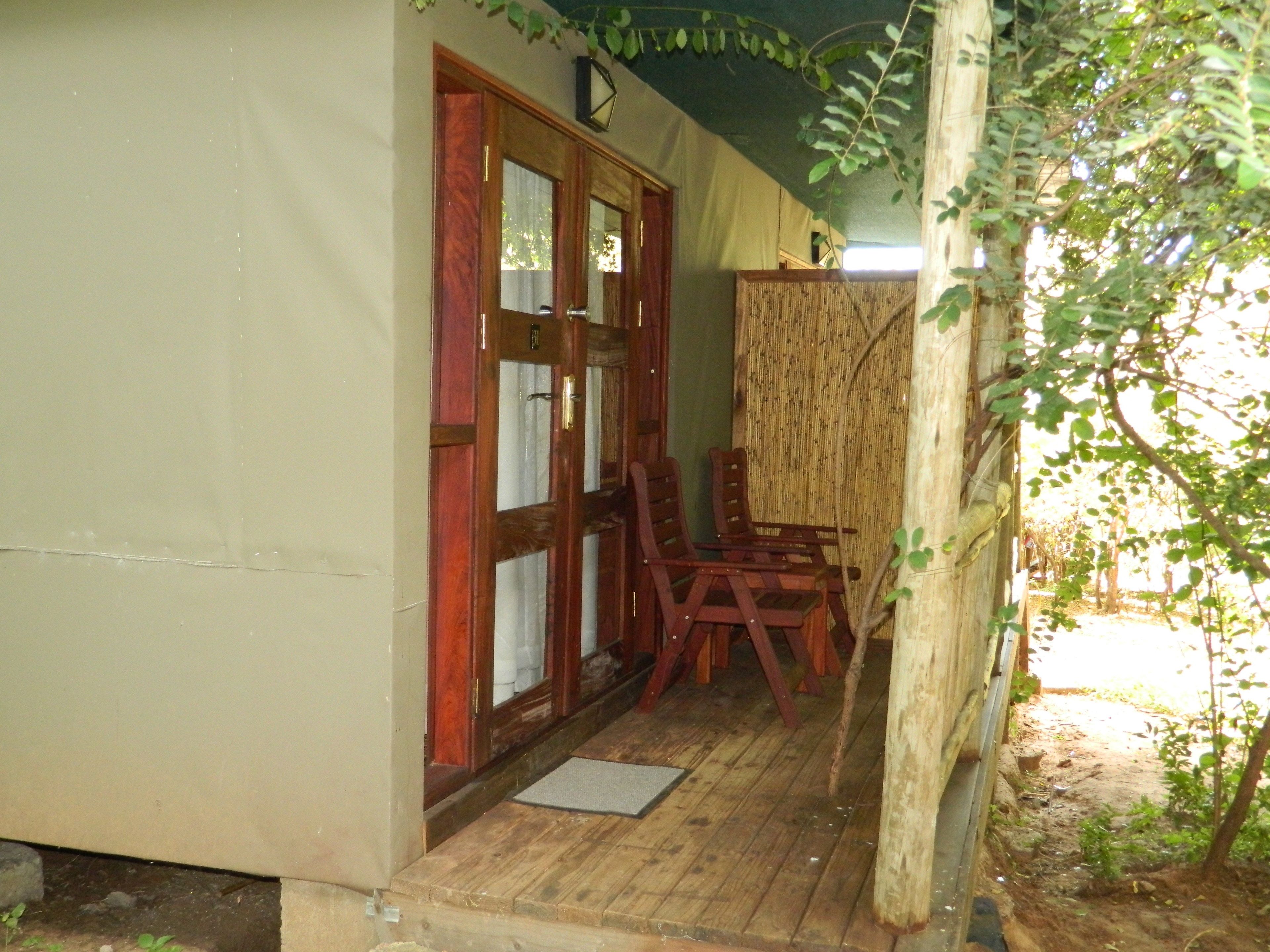 Uma porta de madeira com painéis de vidro, um banco de madeira e uma parede de bambu.