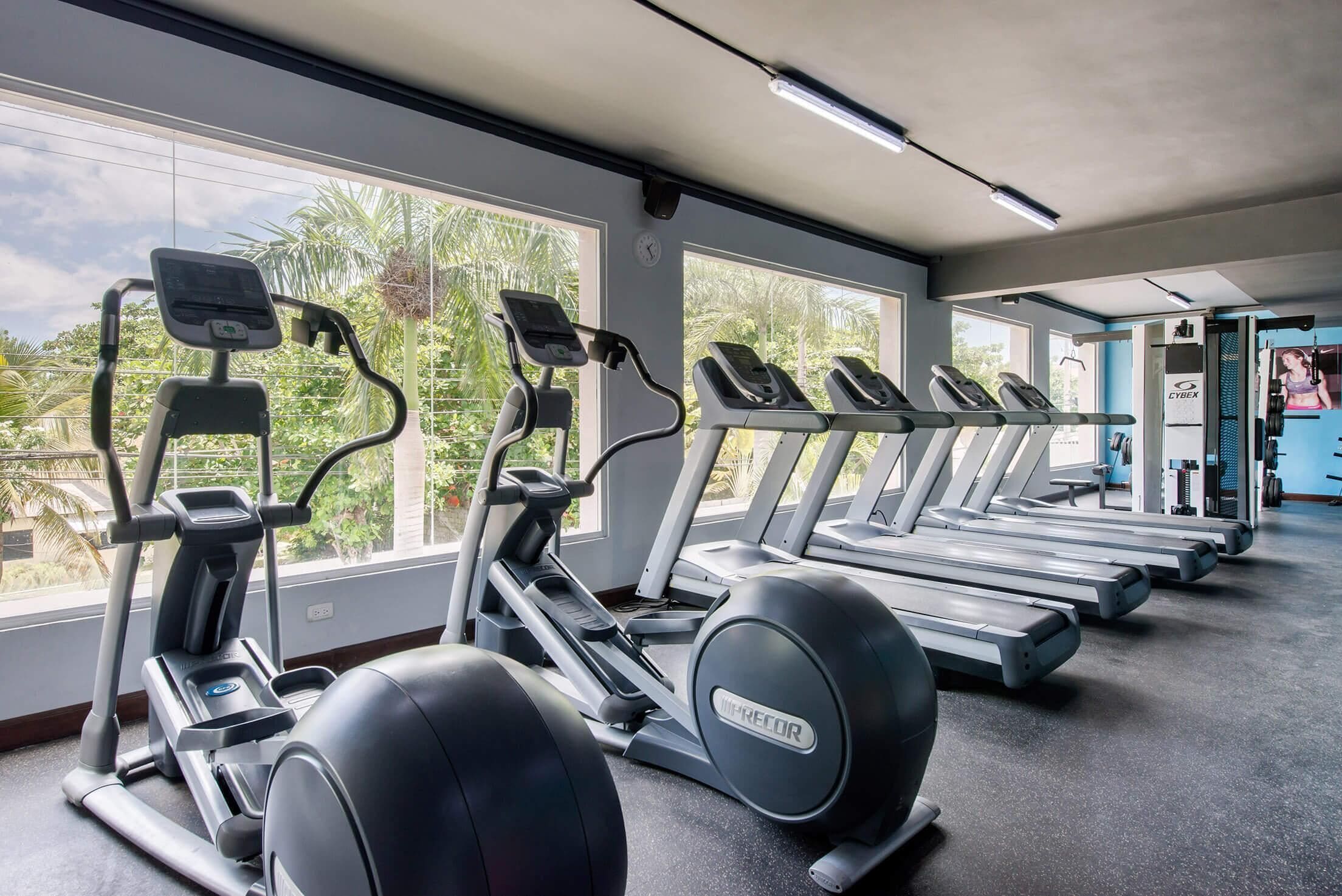 Uma academia com esteiras, elípticos e bolas de exercício.