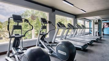 Uma academia com esteiras, elípticos e bolas de exercício.