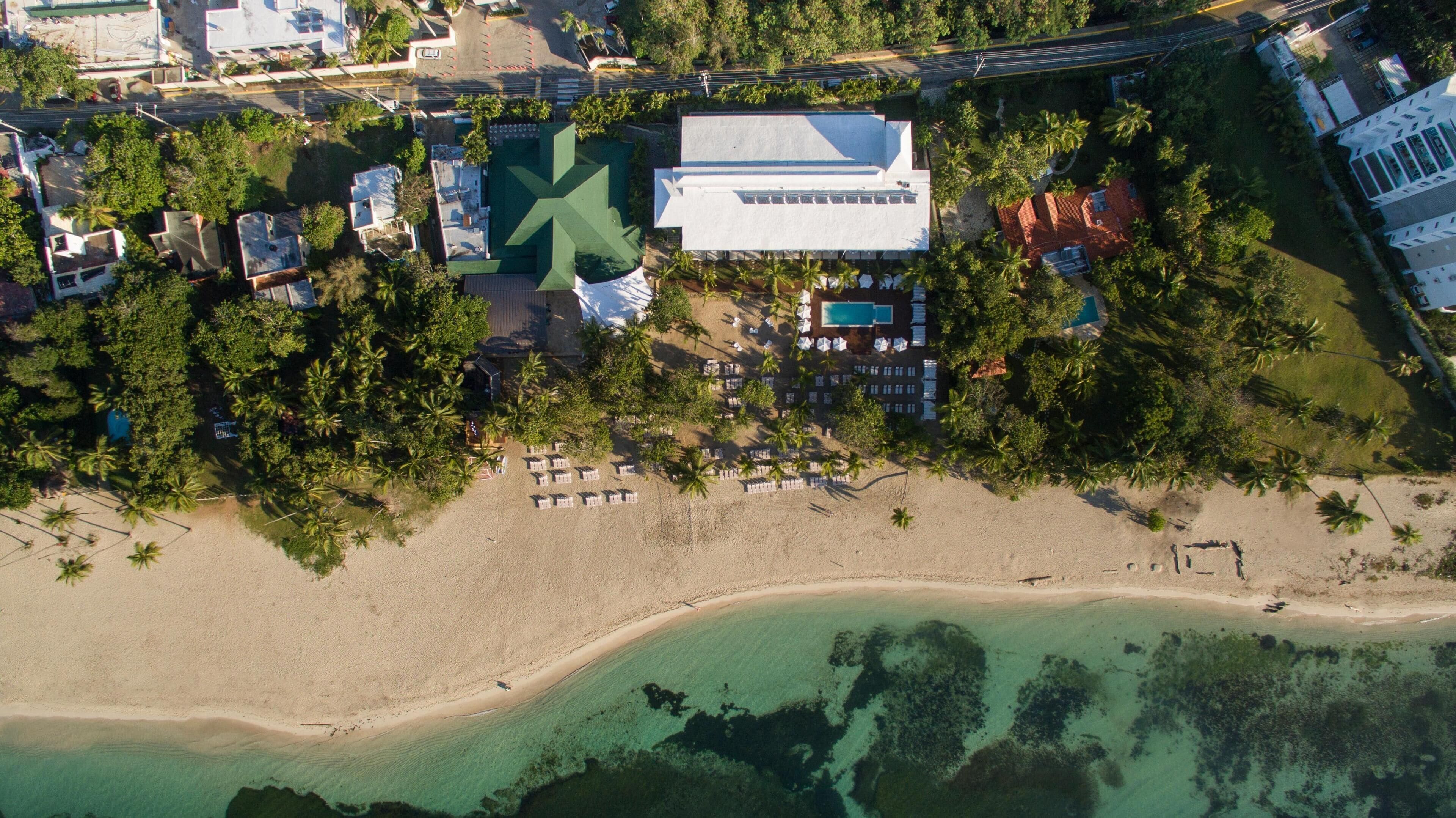 Vista aérea de um resort com um edifício grande, várias piscinas e uma área de praia.