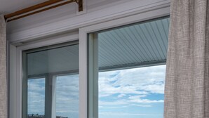 Uma varanda com vista para o oceano, com duas cadeiras e uma mesa.