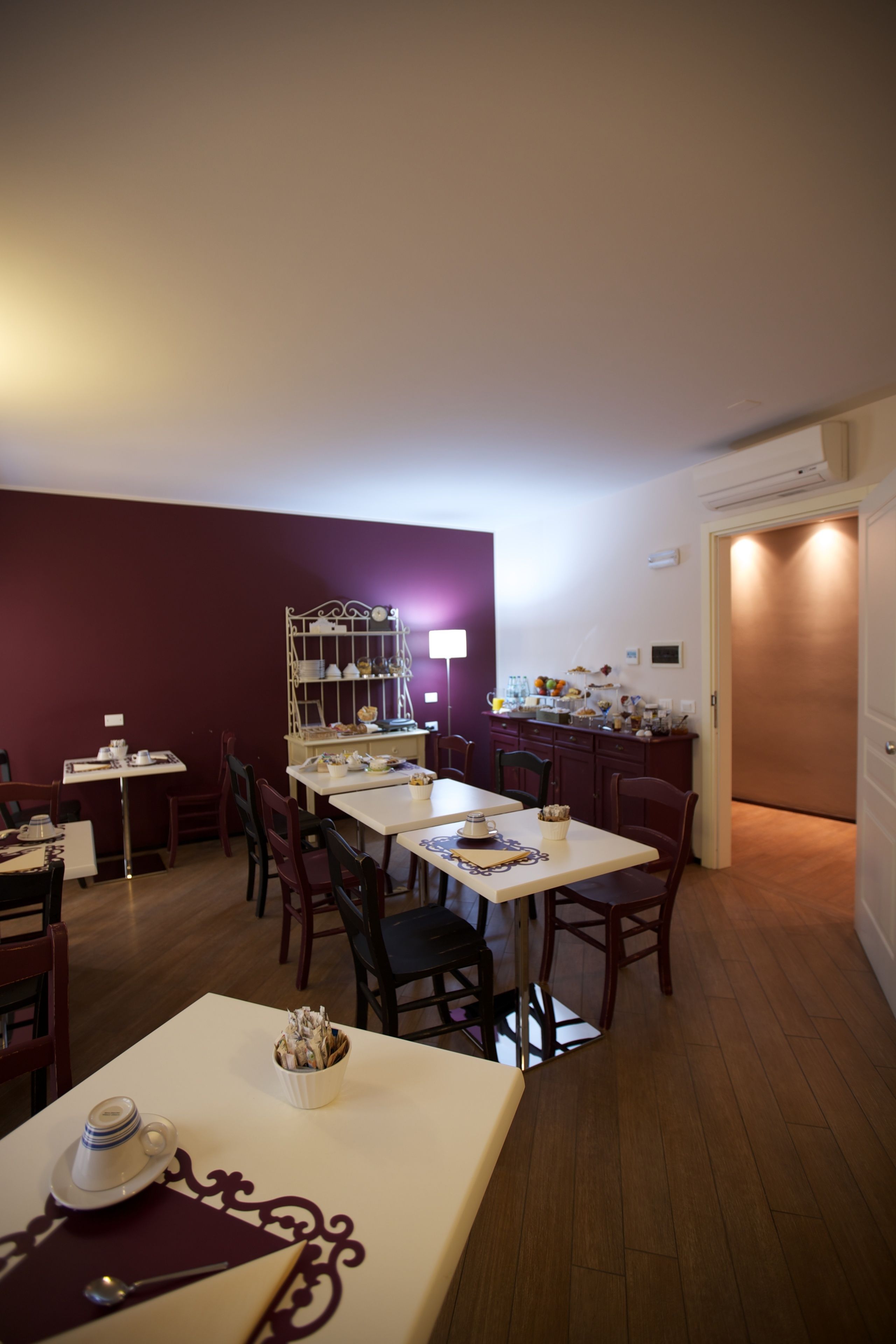 Uma sala de jantar com uma mesa comprida, cadeiras e uma estante de metal decorativa.