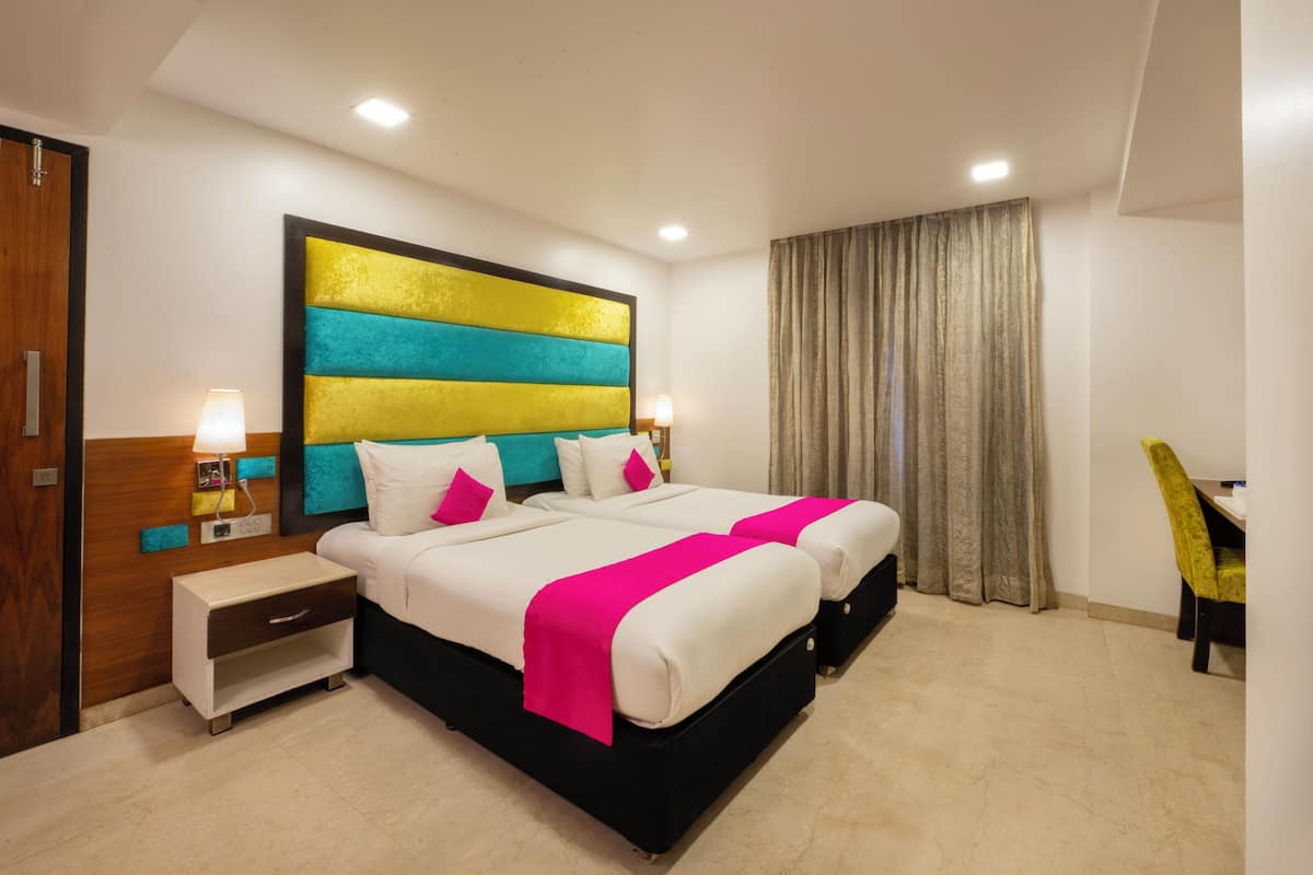 Quarto de hotel com uma cama grande, mesas de cabeceira, uma escrivaninha e uma cadeira.