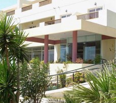 Um edifício moderno com vários andares, grandes janelas e um pátio central com plantas.