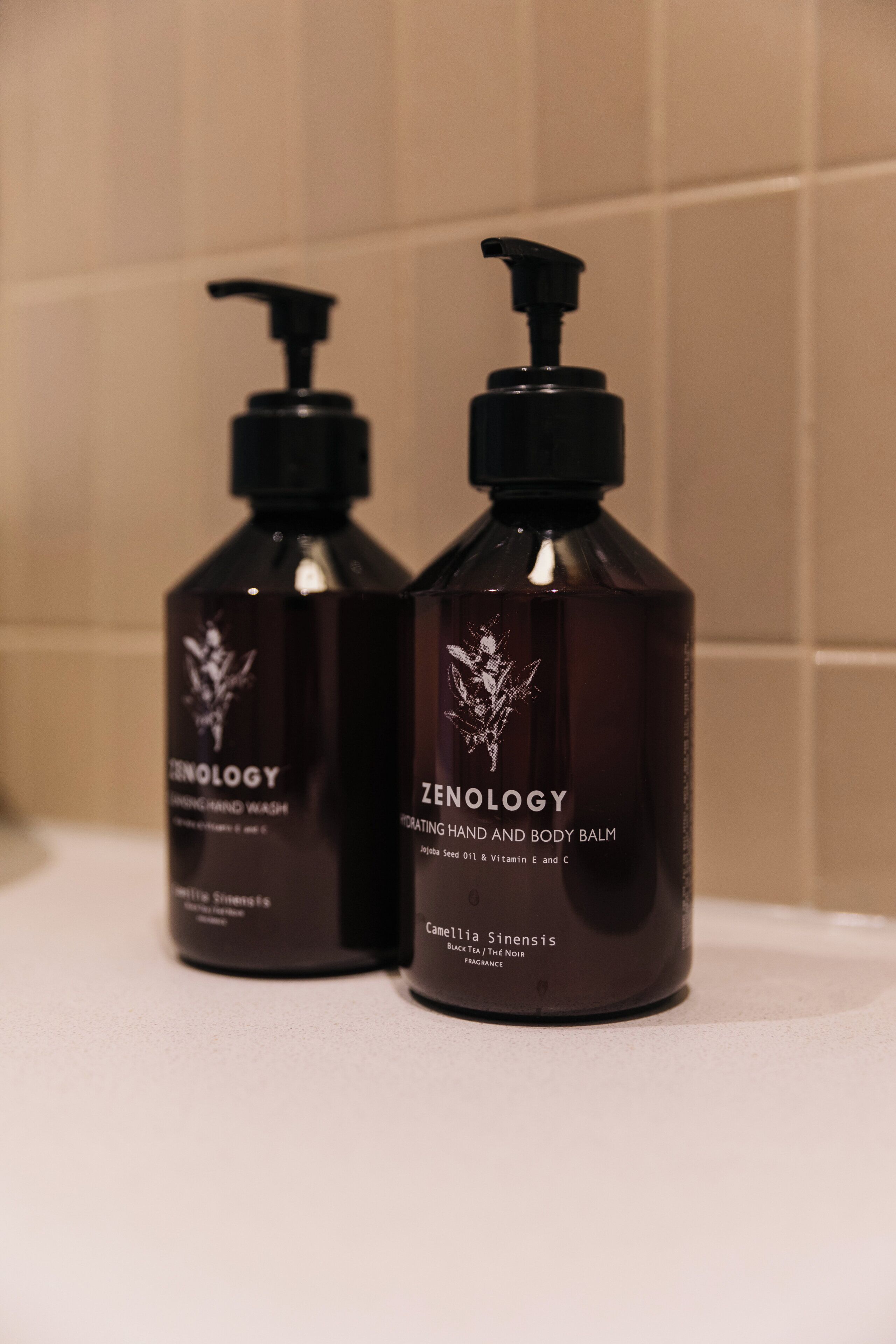 Dois frascos de bálsamo para as mãos e corpo Zenology sobre uma superfície branca.