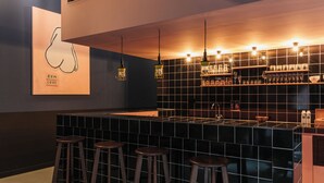 Uma área de bar moderna com painel de azulejos pretos, luminárias pendentes em estilo lanterna e banquetas de bar.