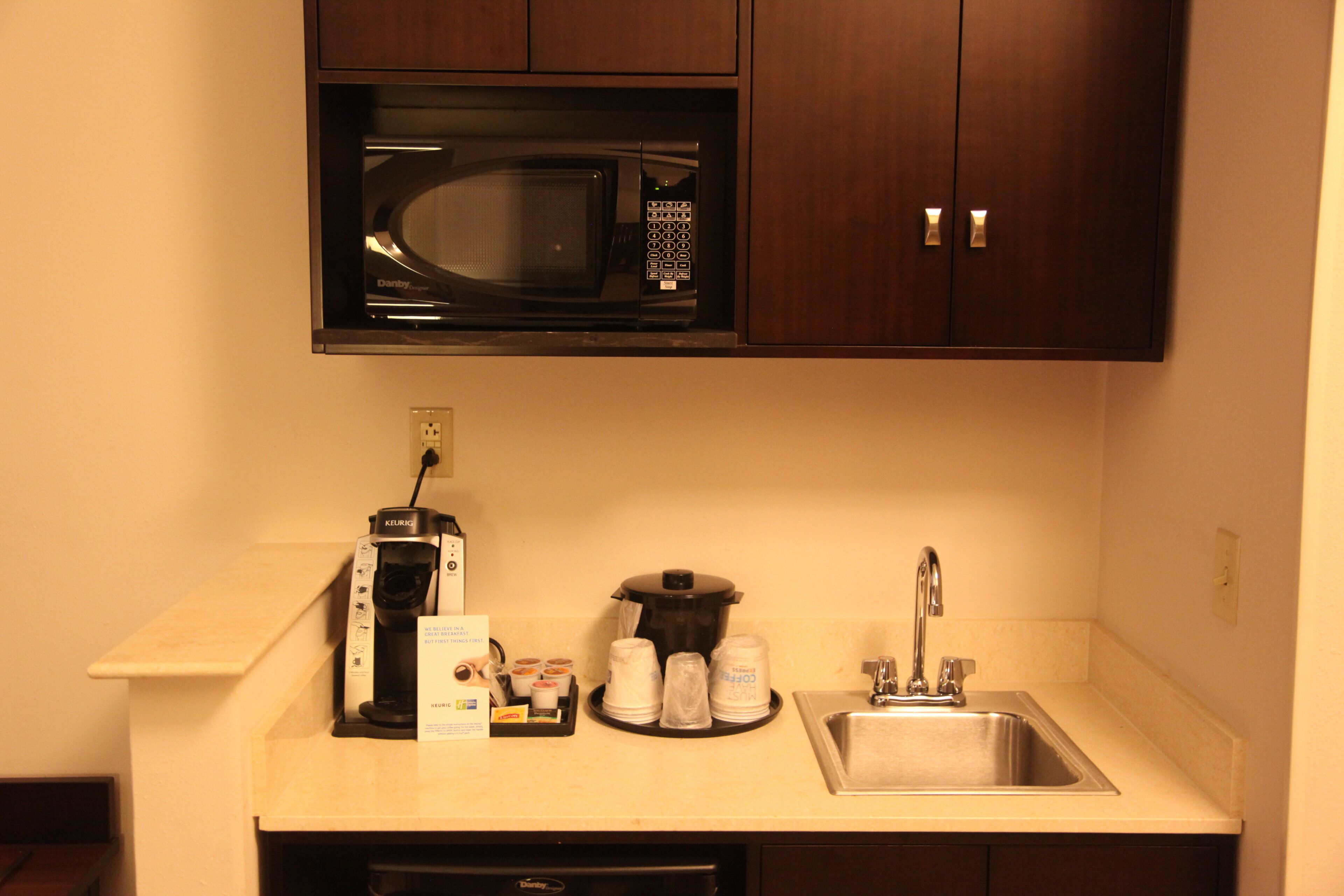 Uma cozinha compacta equipada com micro-ondas, cafeteira e pia.