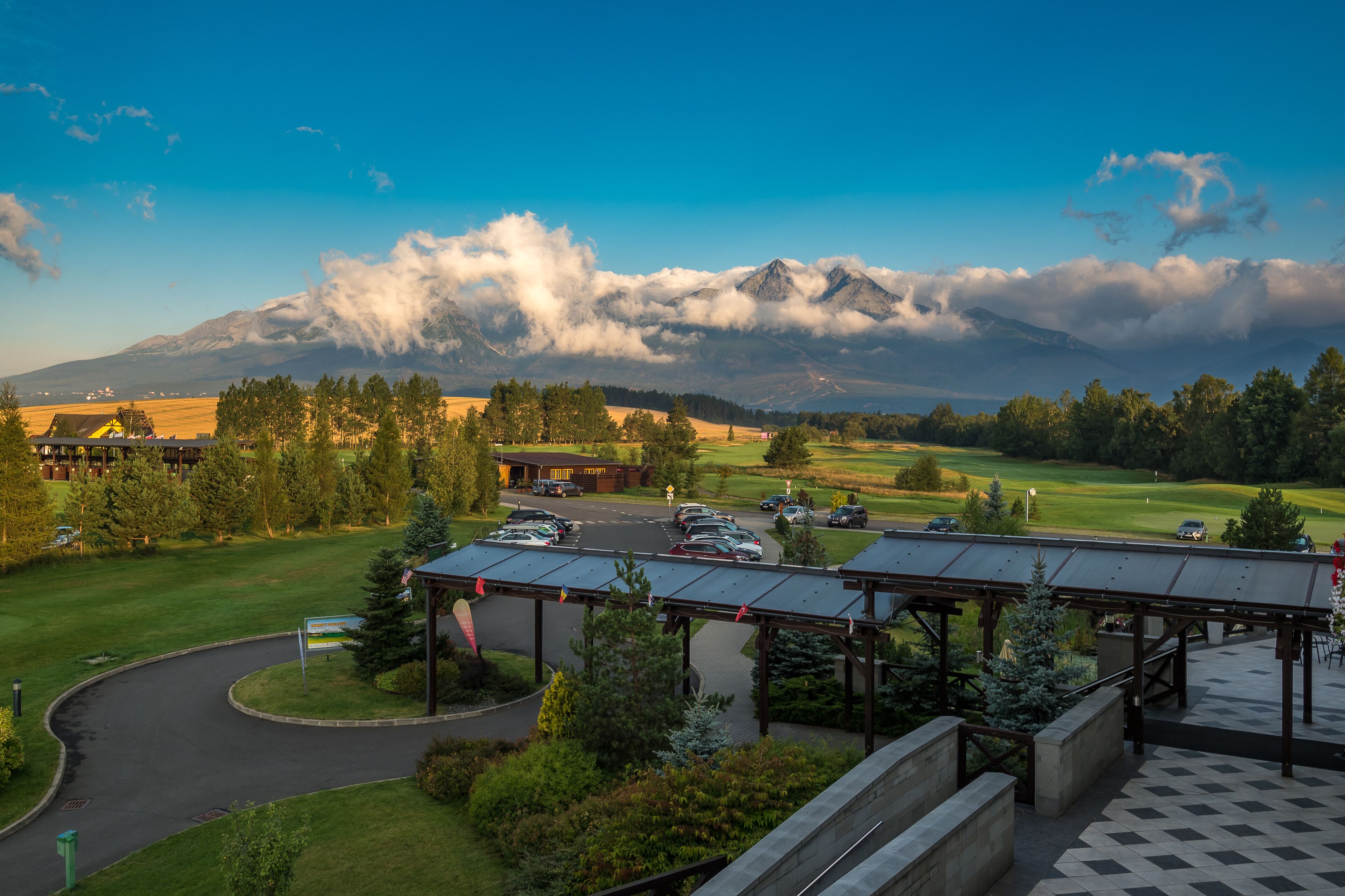 Um campo de golfe com área de estacionamento e vista para montanhas ao fundo.