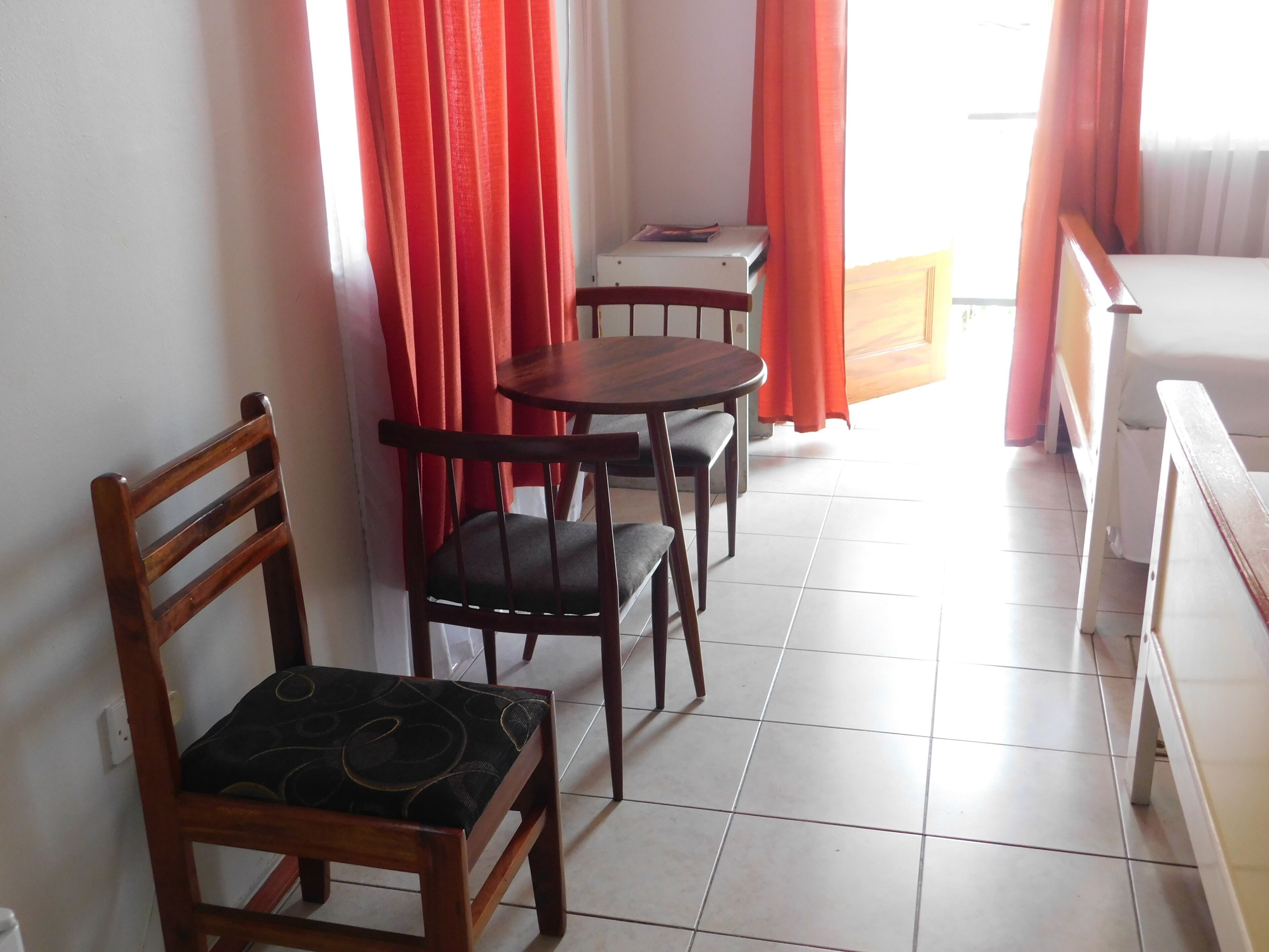 Um quarto com uma cadeira de madeira, uma mesa redonda pequena e uma cama.