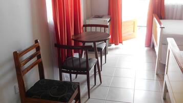 Um quarto com uma cadeira de madeira, uma mesa redonda pequena e uma cama.