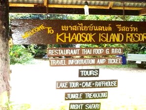 Placa de boas-vindas do Khaosok Island Resort, indicando comodidades como restaurante, informações turísticas e passeios, incluindo passeio de barco pelo lago, gruta e casa de jangadas.