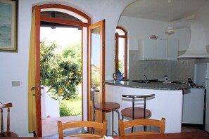 Uma cozinha com área de refeições, uma pequena ilha e vista para o verde lá fora.