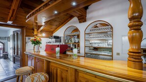 Um balcão de madeira com banquetas, um frigorífico e estantes com copos.