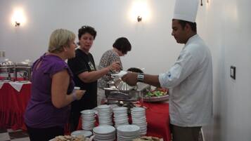 Uma mesa de buffet com vários pontos de comida e pessoas presentes.