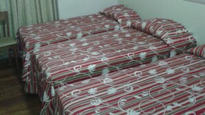 Quarto com duas camas, uma cadeira, um quadro de rosas e um ar condicionado.