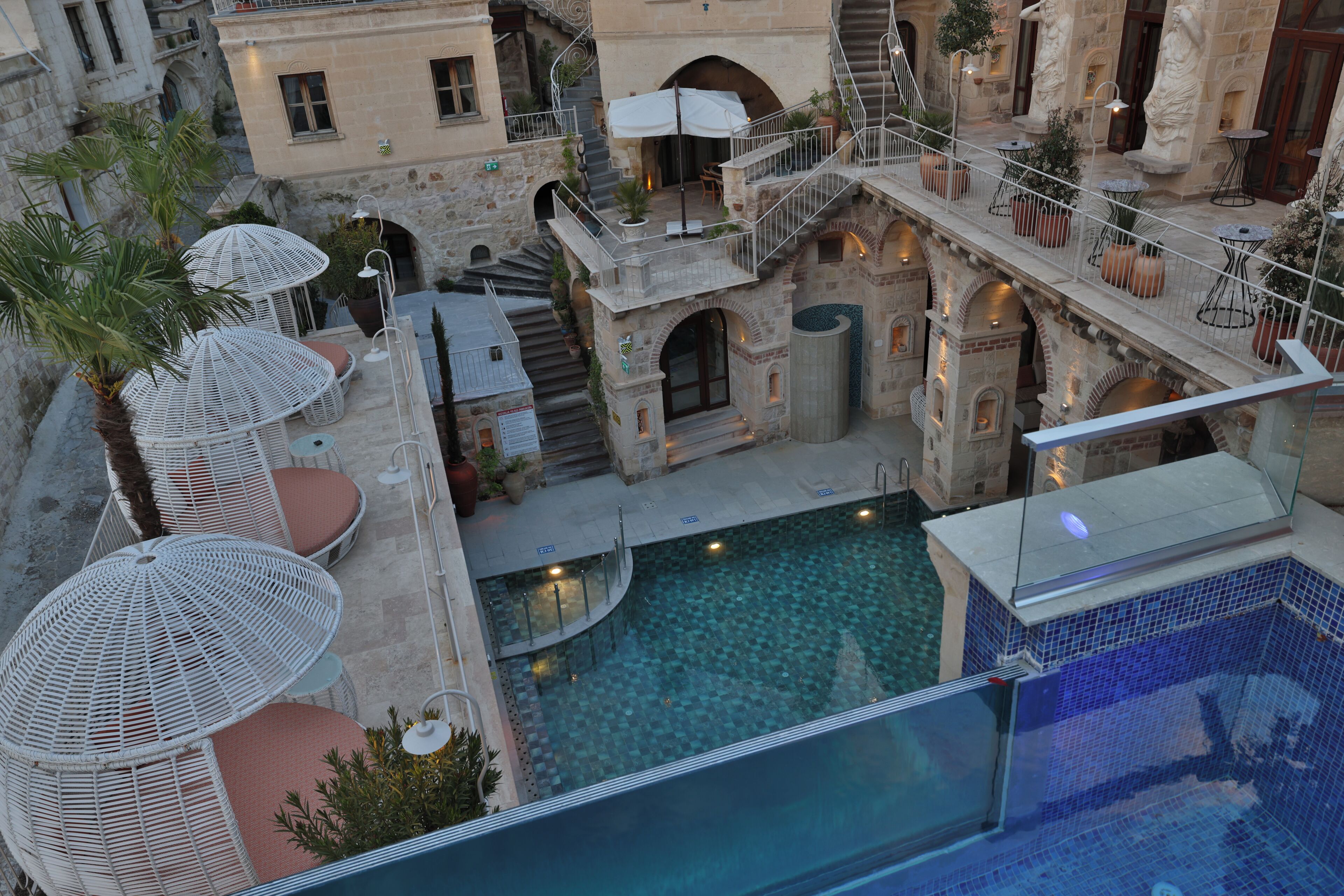 Piscina no terraço com balaustrada de pedra, cadeiras de descanso e plantas em vasos.