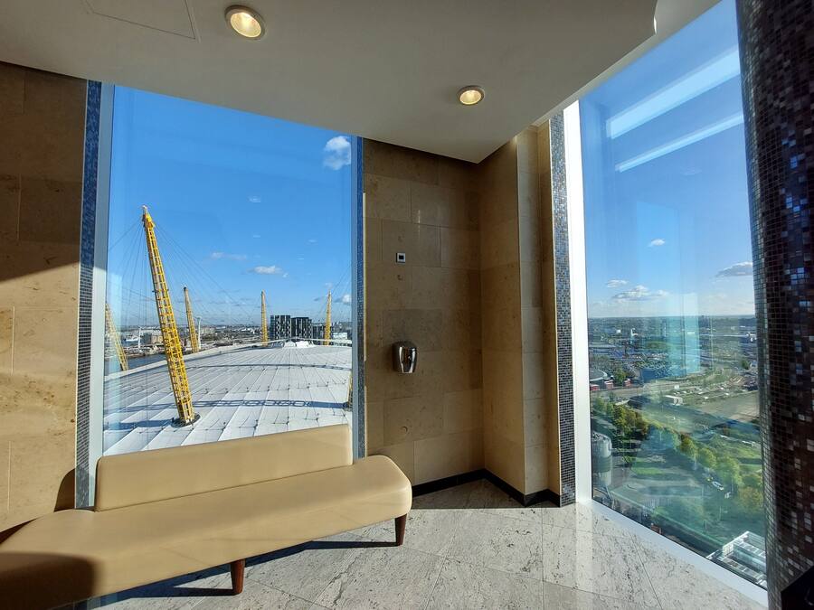 Quarto de hotel moderno com uma grande janela que oferece vista para um canteiro de obras e para a paisagem urbana.