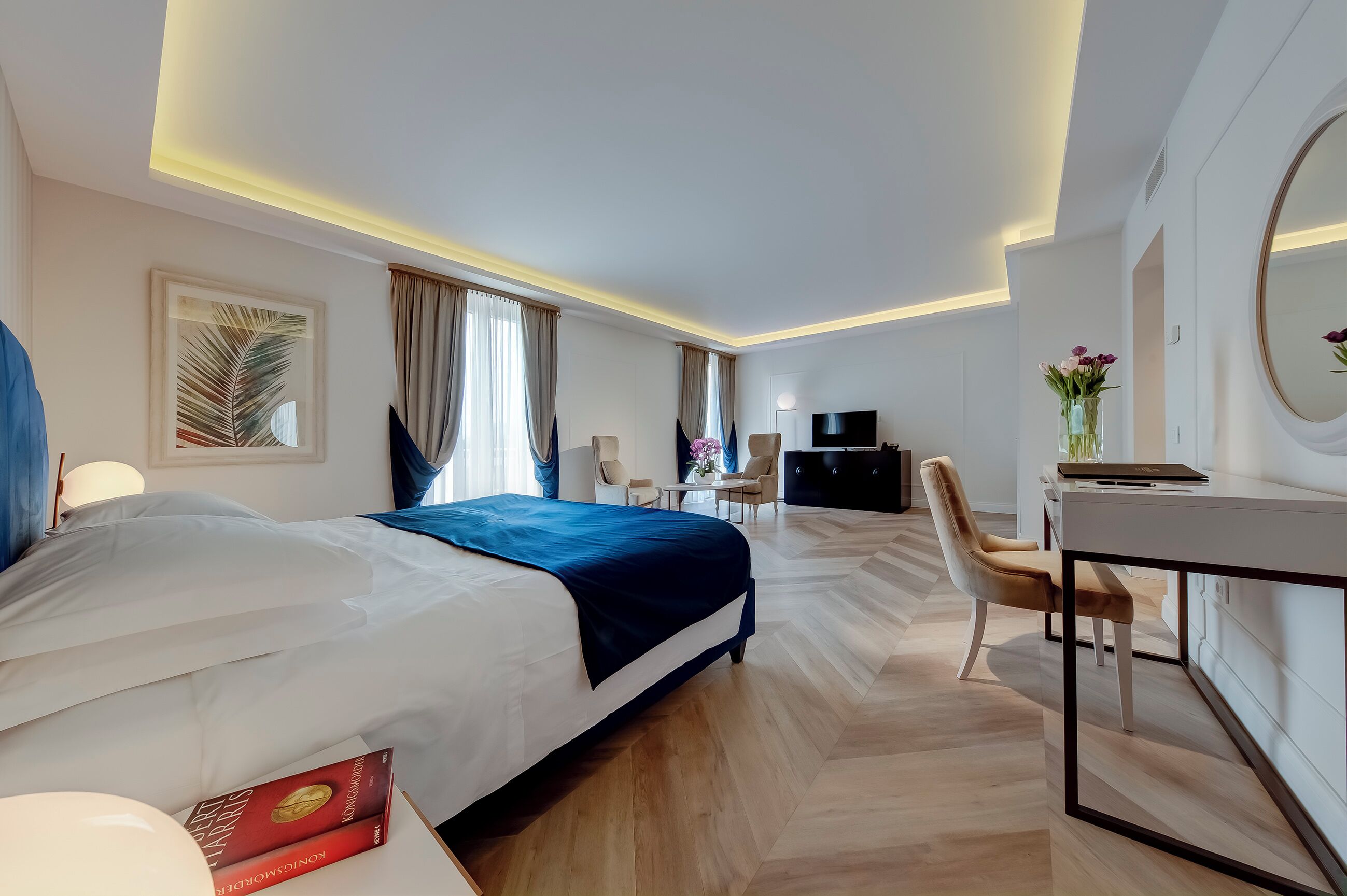 Quarto de hotel moderno com uma cama grande, uma escrivaninha, uma cadeira, uma televisão e um espelho.