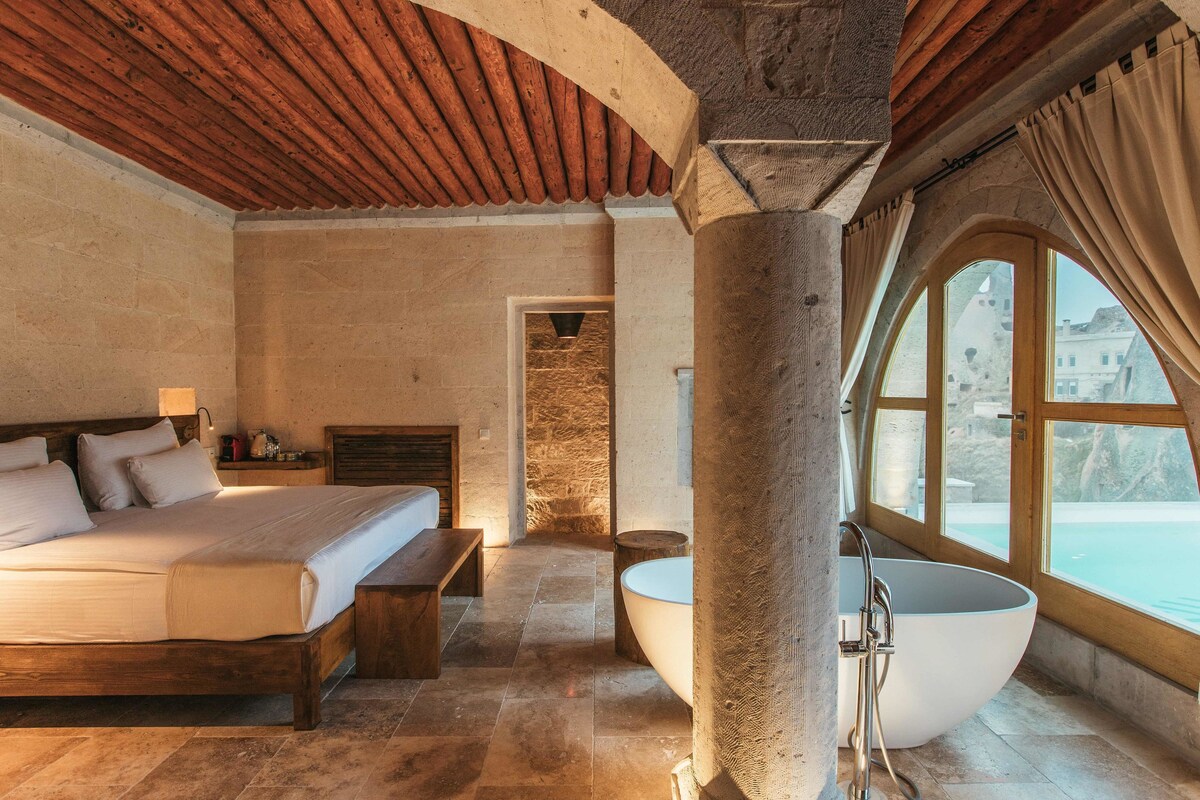 Quarto com uma cama grande, banheira e parede de pedra.