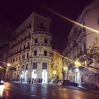 Um edifício histórico com vários andares e estilo arquitetônico clássico, com varandas e janelas grandes.