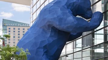 Uma escultura geométrica azul em frente a um edifício com uma placa que diz 'HYATT PLACE'.
