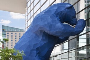 Uma escultura geométrica azul em frente a um edifício com uma placa que diz 'HYATT PLACE'.