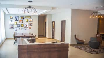 Uma sala de estar moderna com uma ilha central, uma área de jantar com uma mesa comprida e um espaço de estar com duas cadeiras.