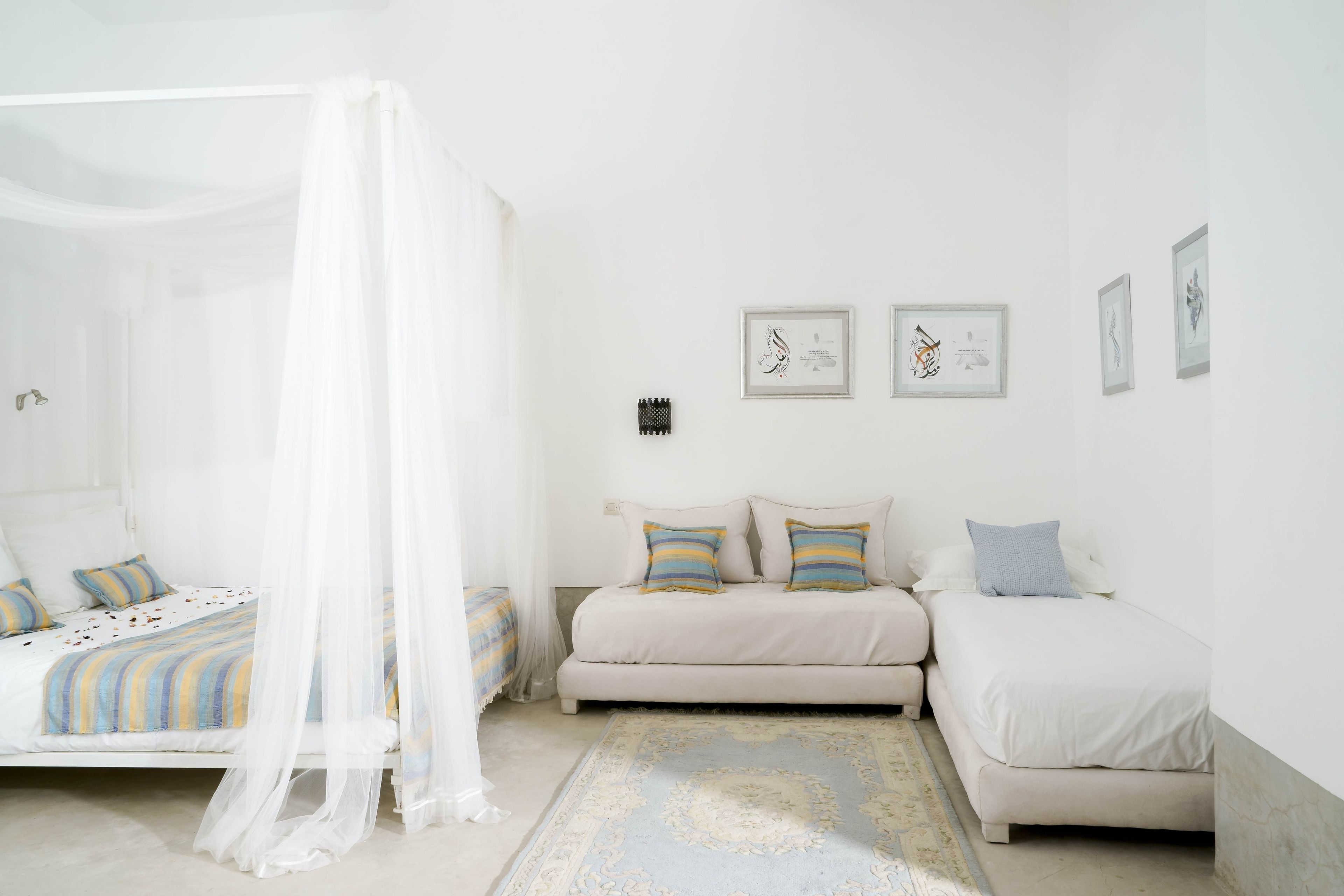 Quarto com cama, sofá, mesa de cabeceira e prateleira na parede.