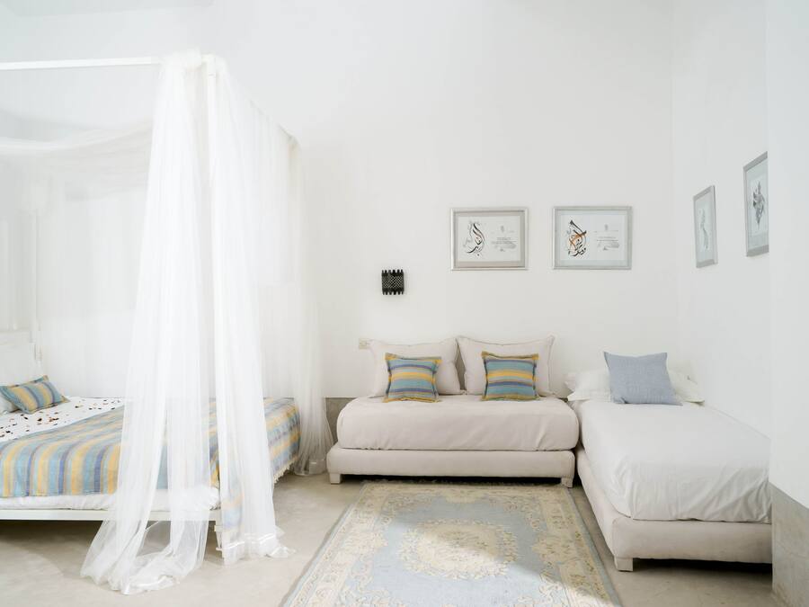 Quarto com cama, sofá, mesa de cabeceira e prateleira na parede.
