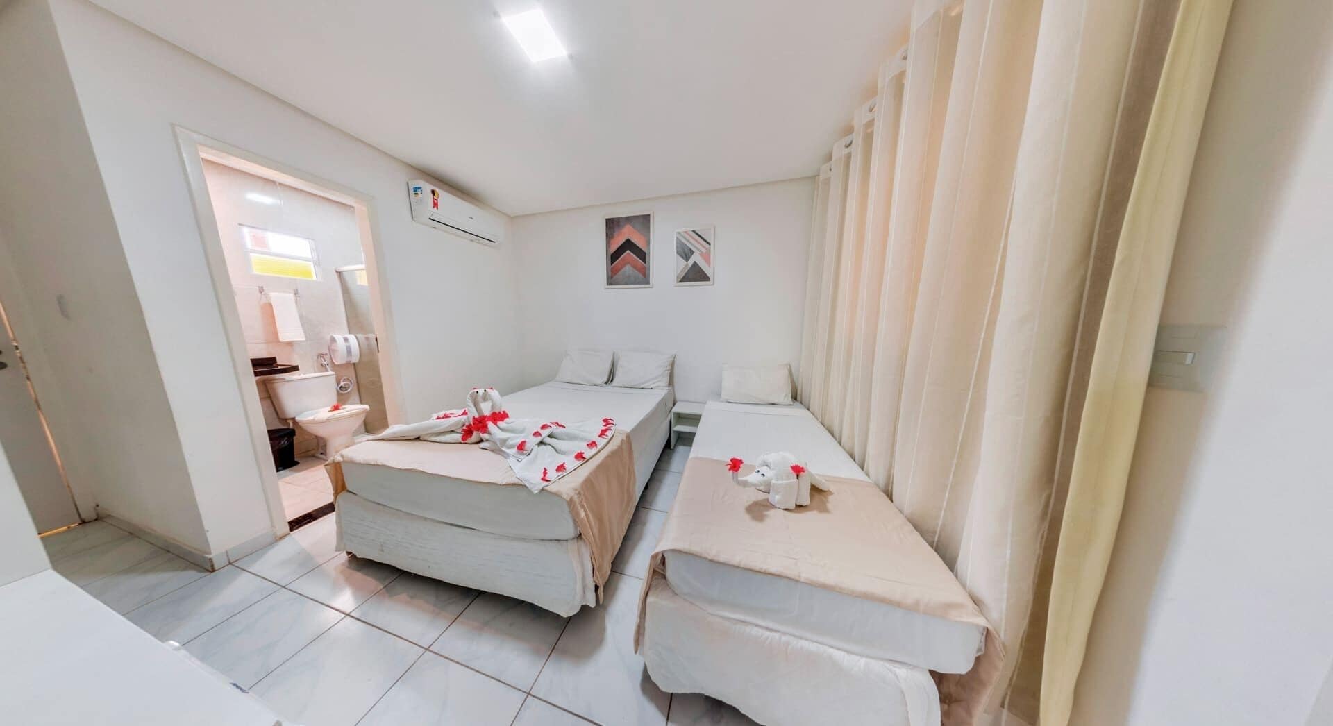 Quarto de hotel com duas camas, banheiro e uma pequena área de estar.