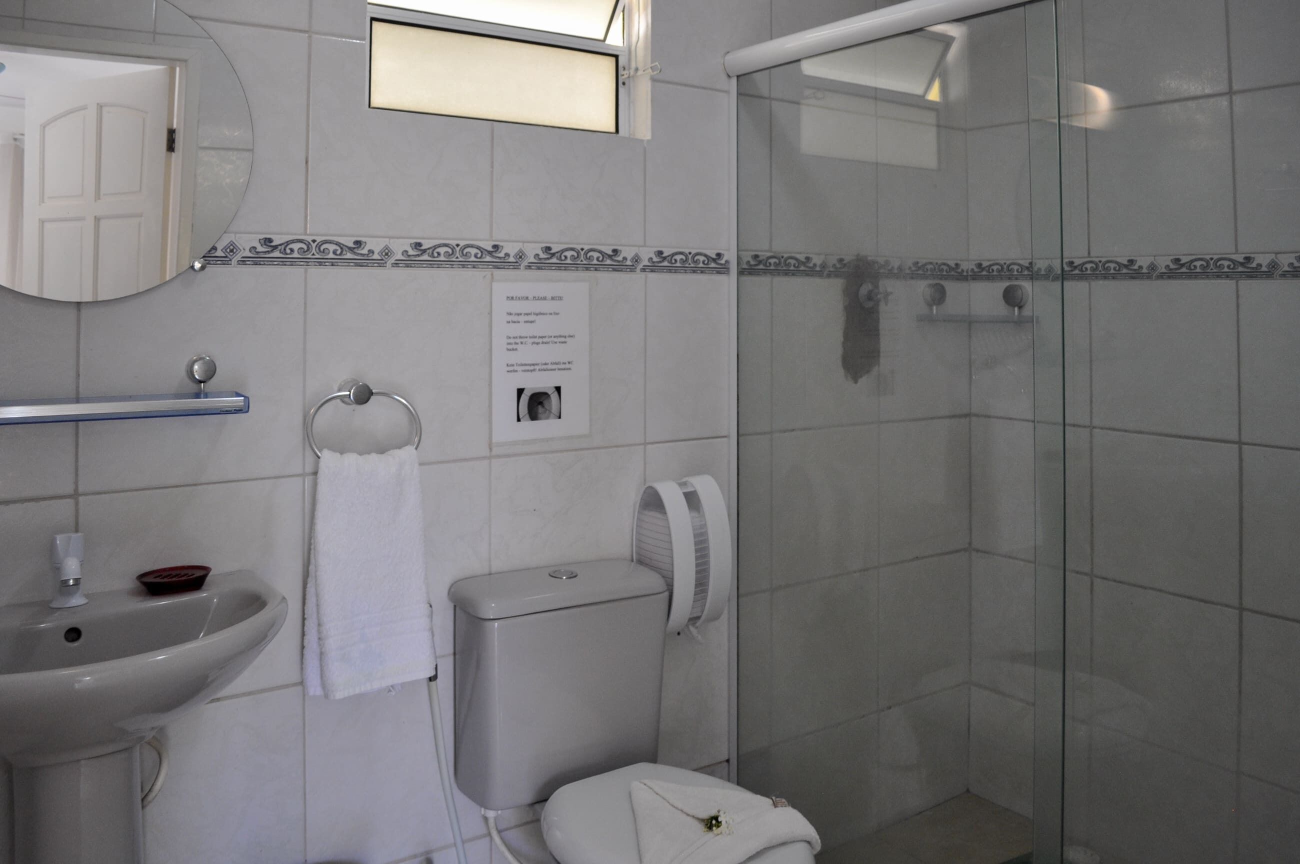Casa de banho com sanita, lavatório e cabine de duche de vidro.