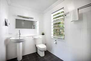 Casa de banho moderna com uma sanita, lavatório e janela com persianas.
