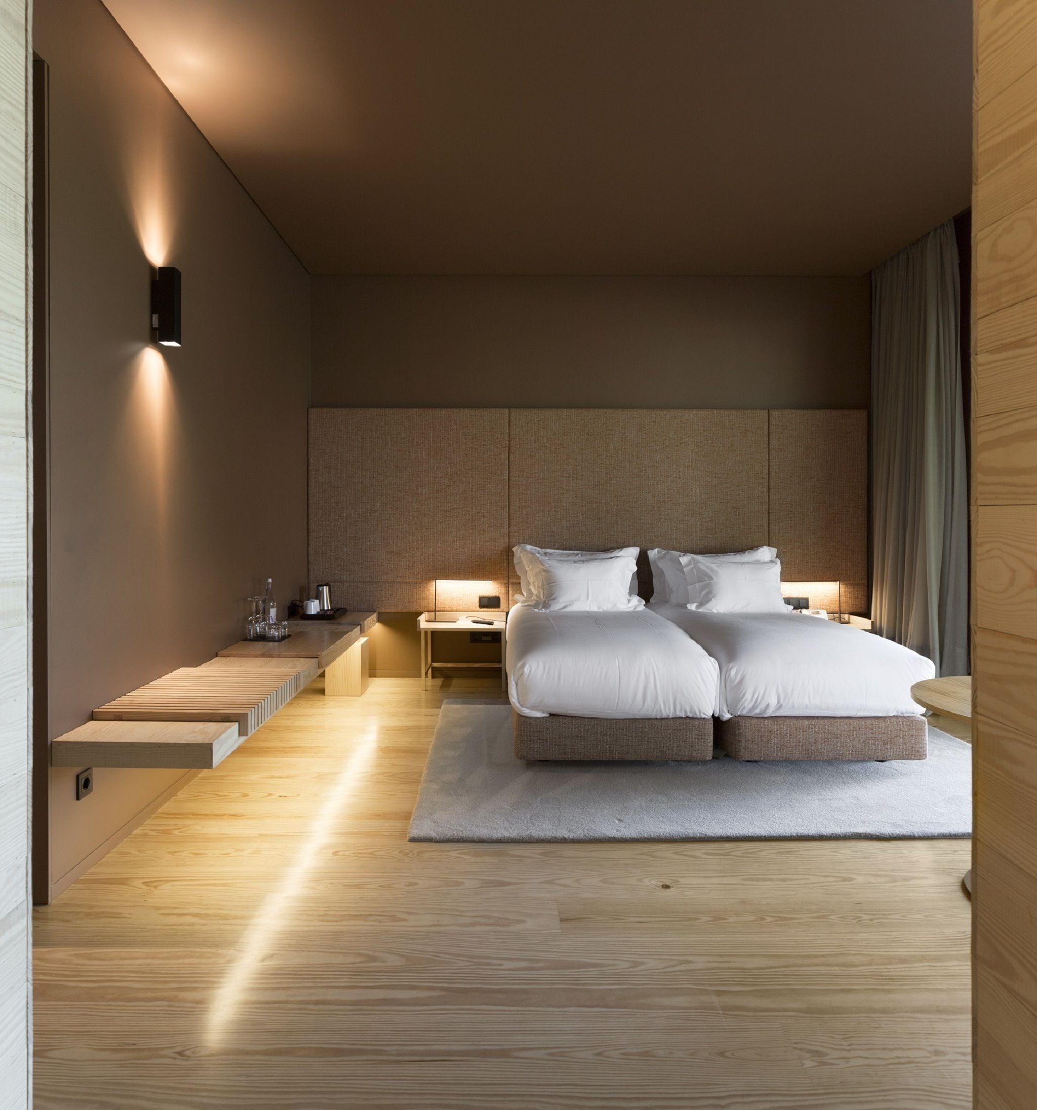 Um quarto moderno com uma cama grande, mesas de cabeceira e iluminação embutida.